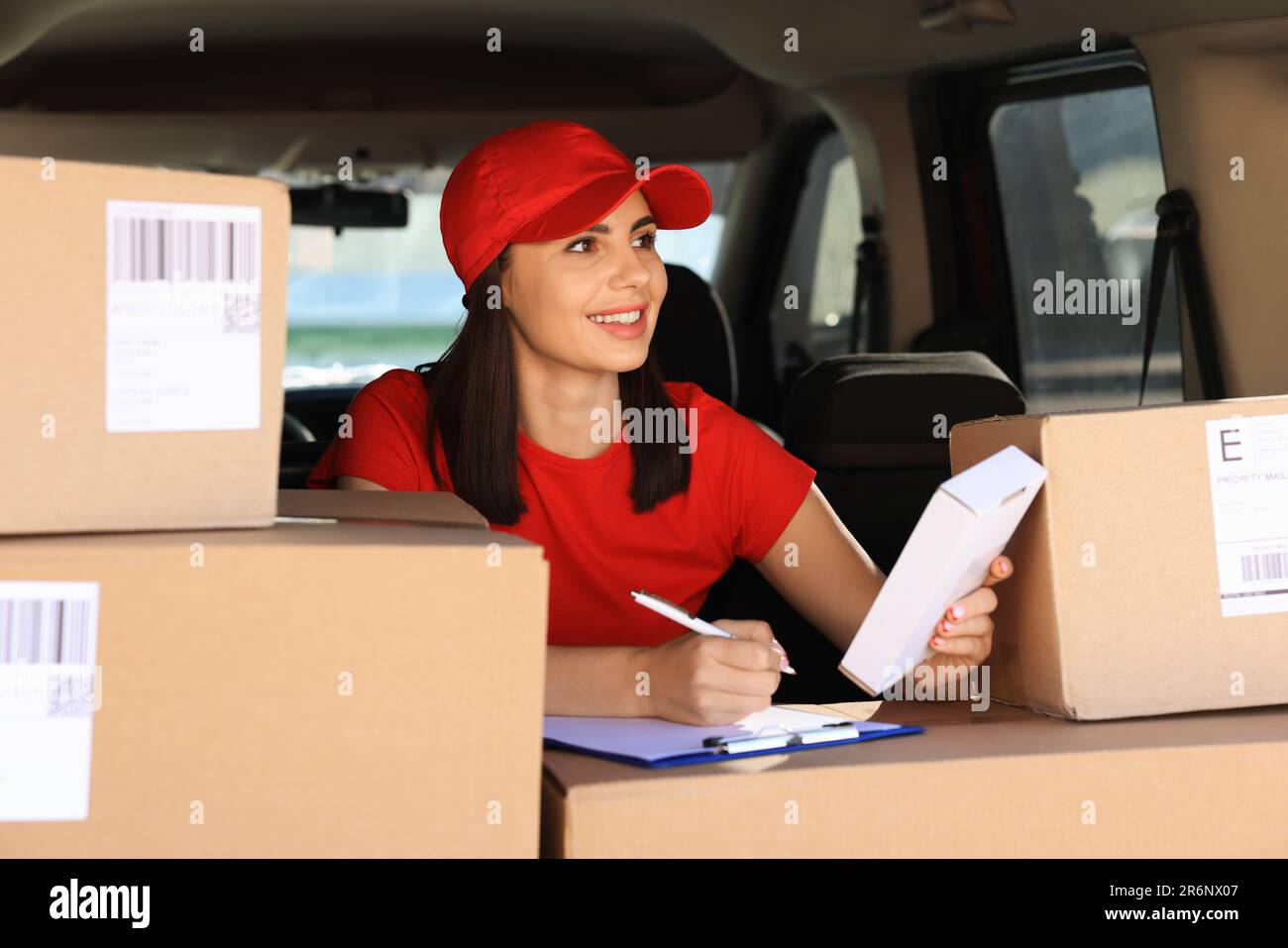 Courier with clipboard checking packages in delivery van Stock Photo ...