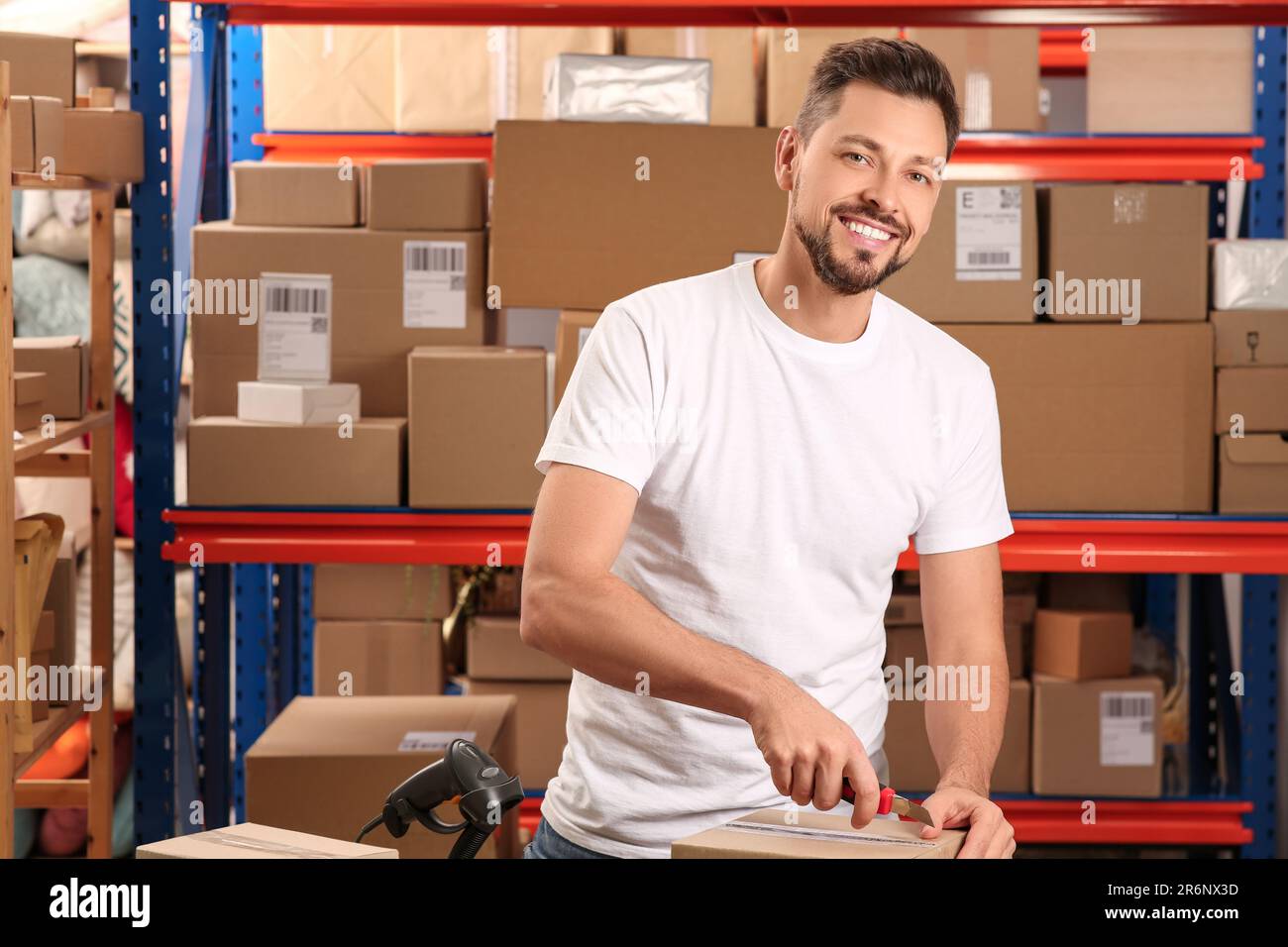 Post office worker with utility knife opening parcel indoors Stock ...