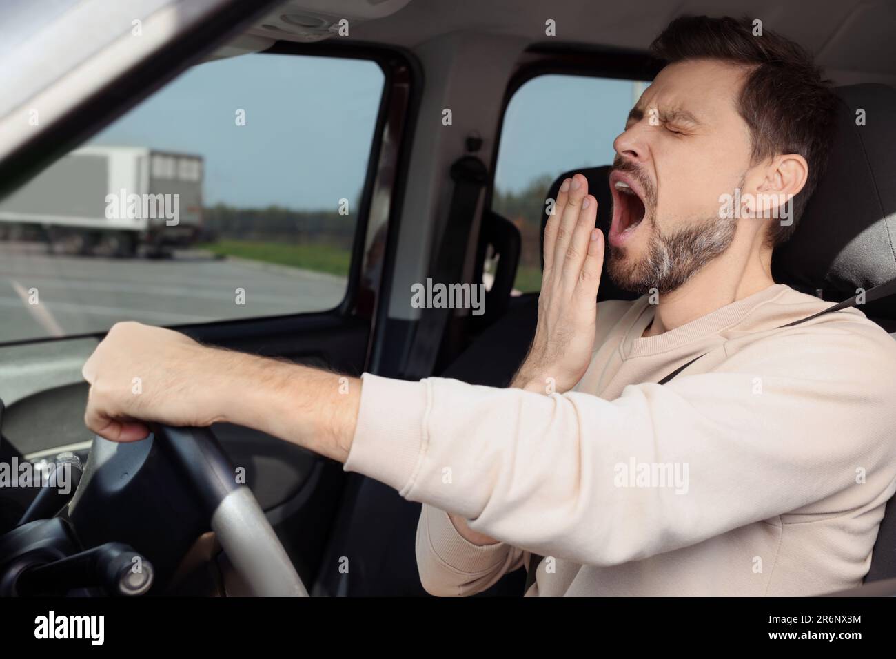 Sleepy man yawning while driving his car Stock Photo - Alamy