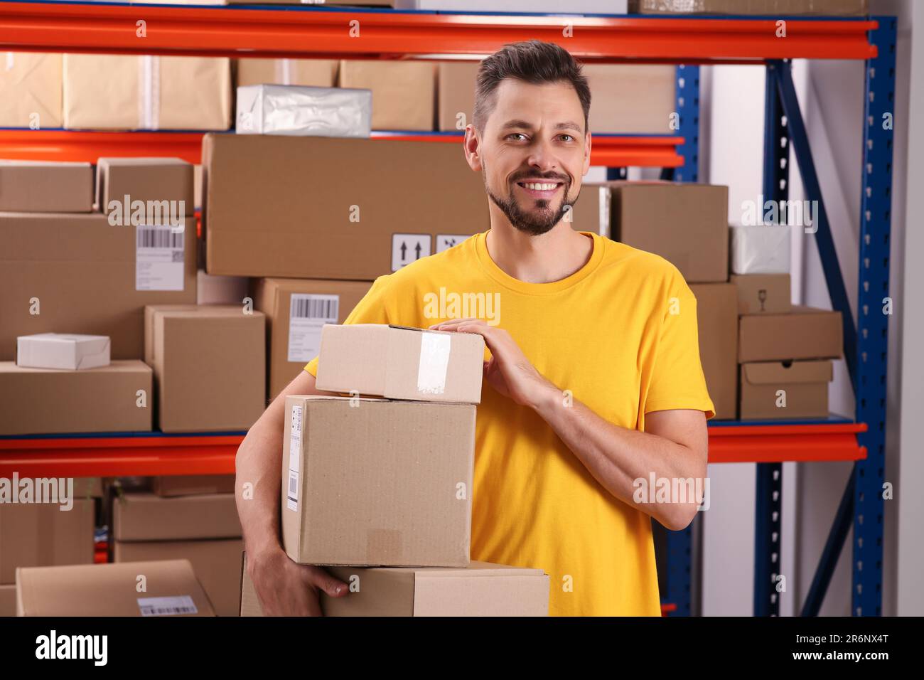 Post office worker with parcels near rack indoors Stock Photo - Alamy