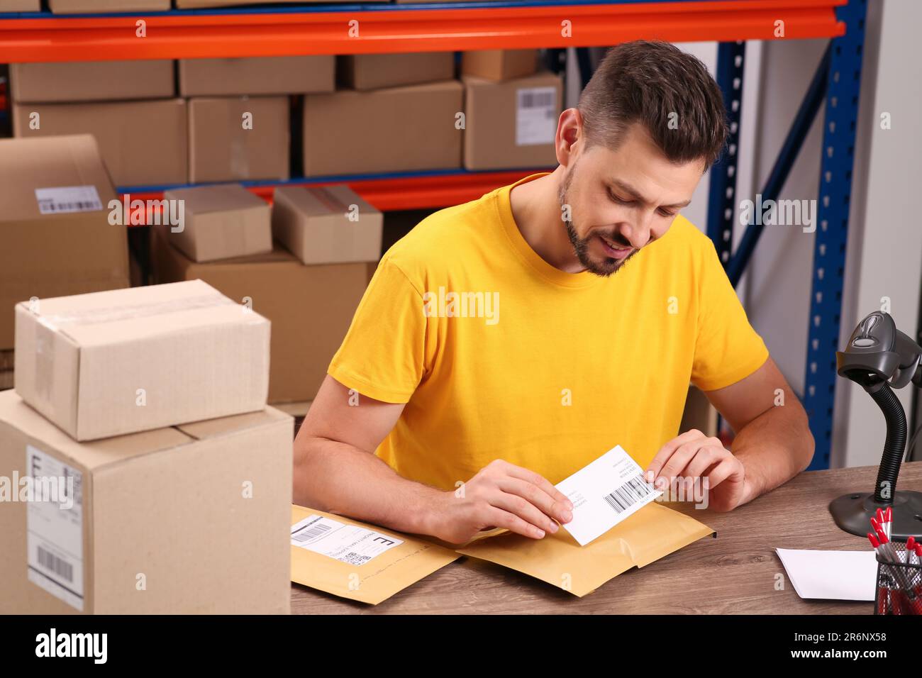 Post office worker sticking barcode on parcel at counter indoors Stock ...