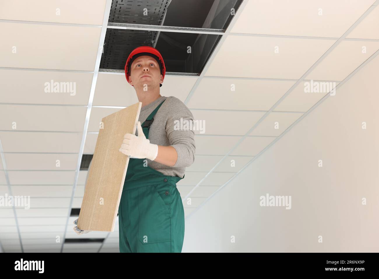 Suspended ceiling installation. Builder working with PVC tile Stock ...