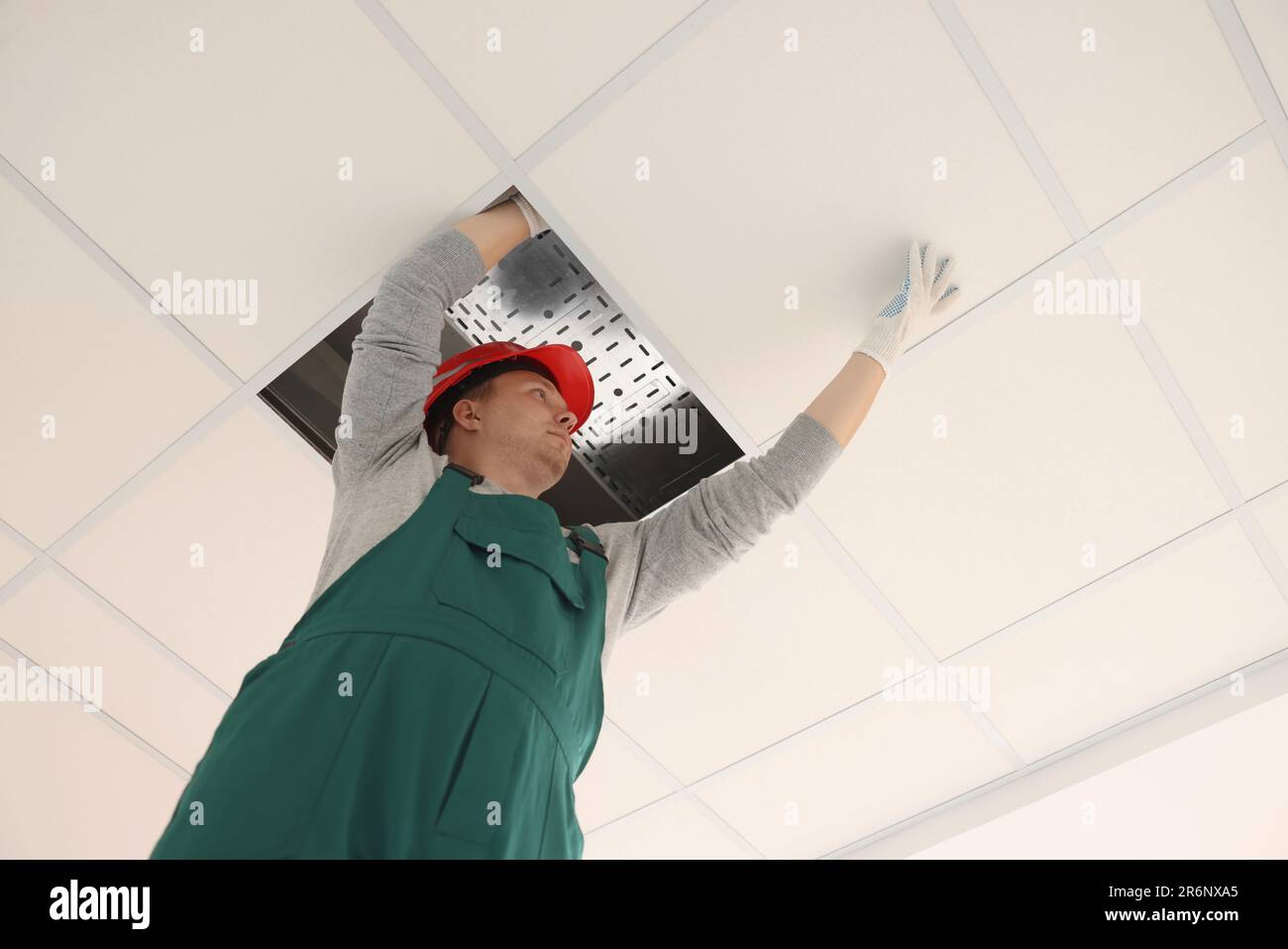 Suspended ceiling installation. Builder working with PVC tile, low ...