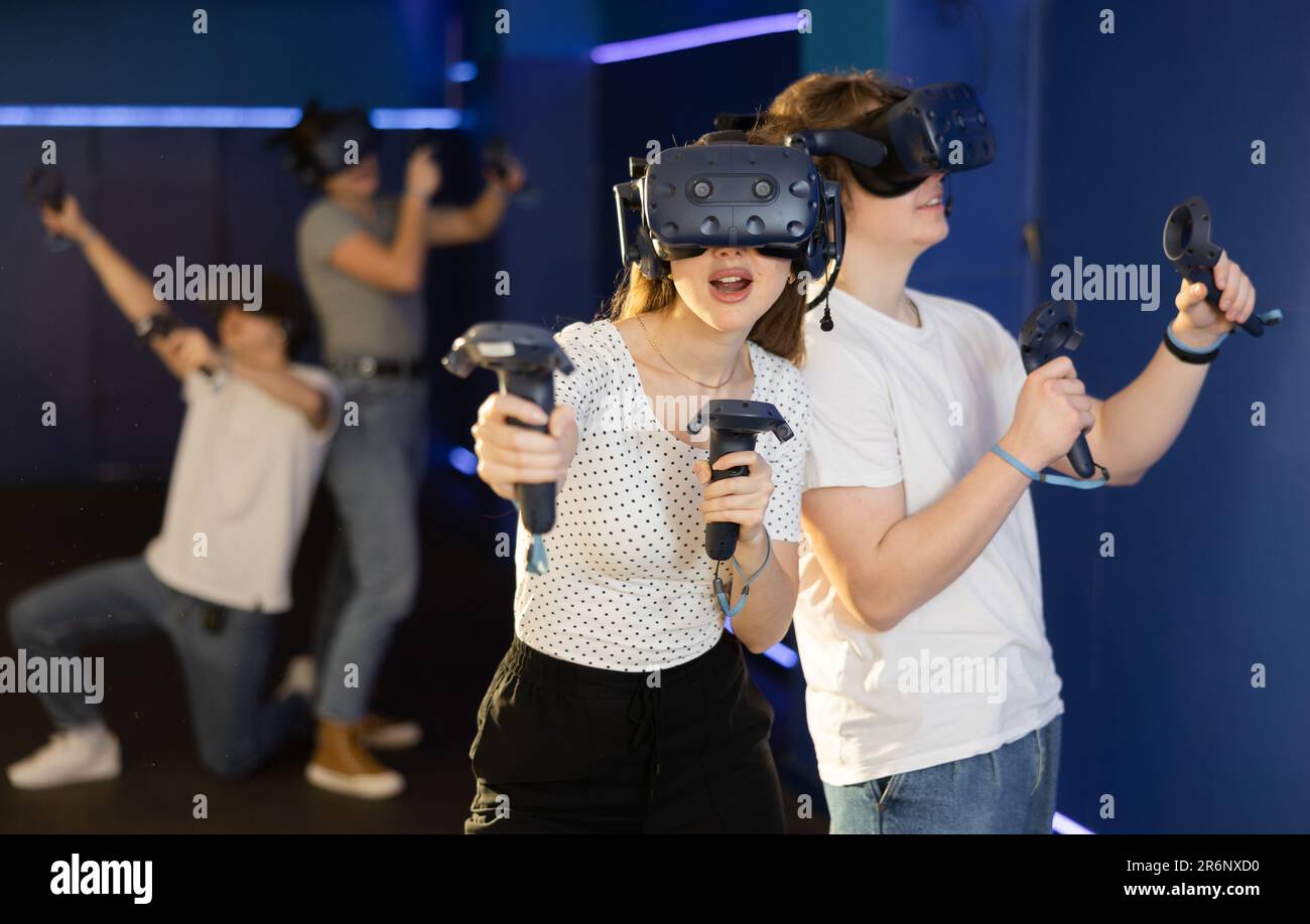 Young guy and girl in vr headset stand shoulder to shoulder interacting ...