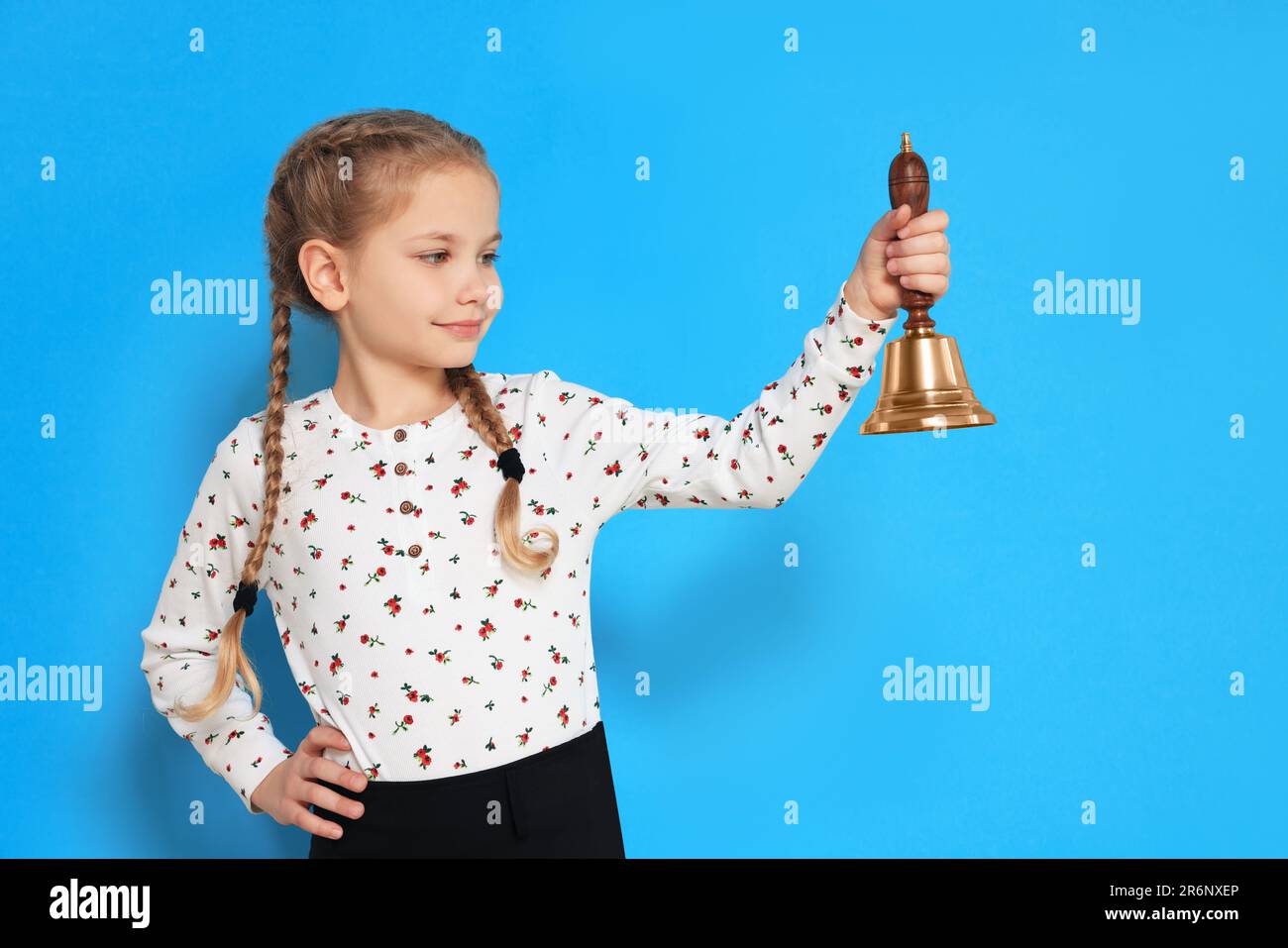 Pupil with school bell on light blue background Stock Photo - Alamy