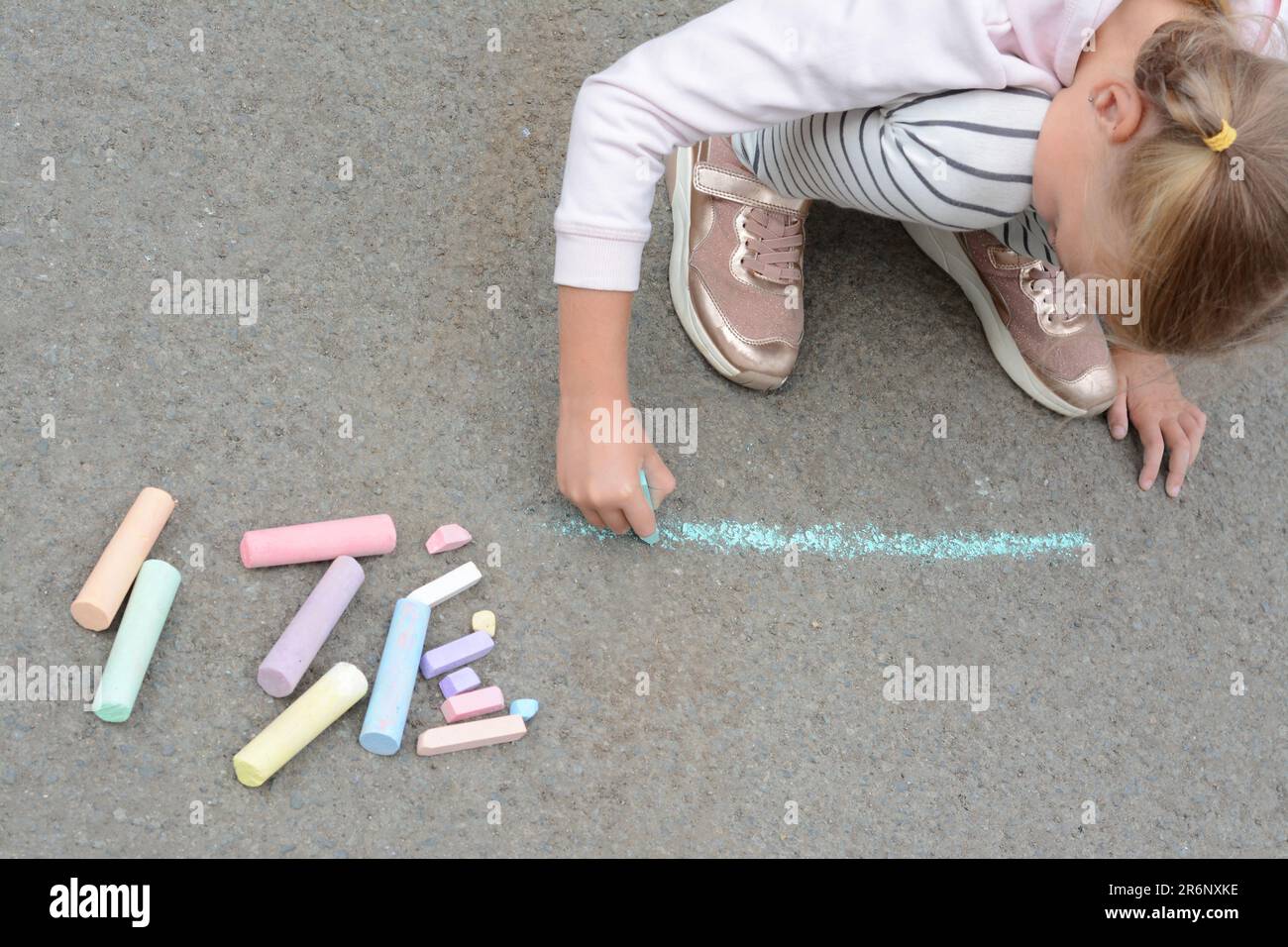 Little child drawing happy family with chalk on asphalt, above view ...