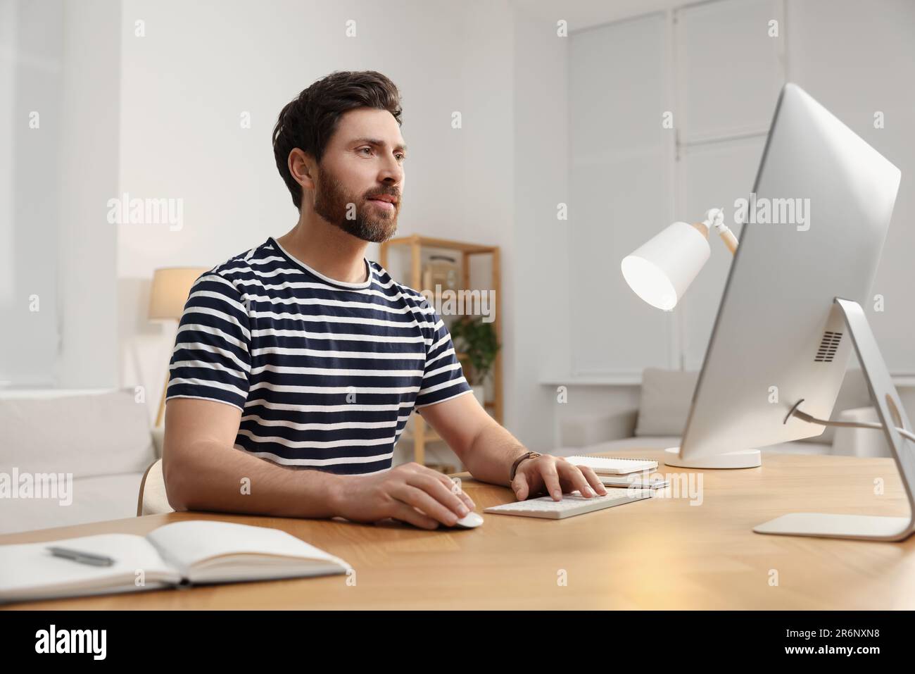 Home workplace. Man working with computer at wooden desk in room Stock ...
