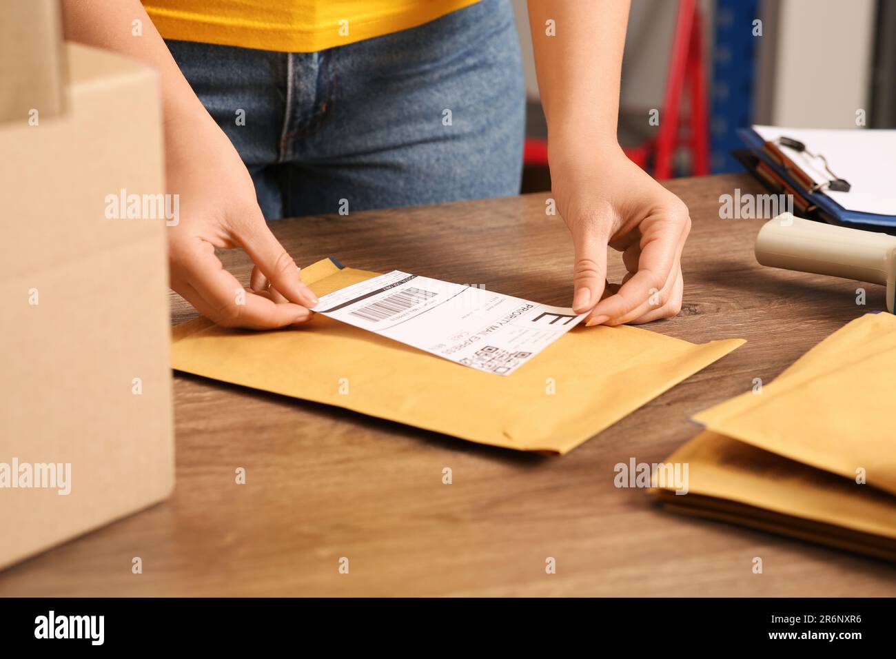 Post office worker sticking barcode on parcel at counter indoors ...
