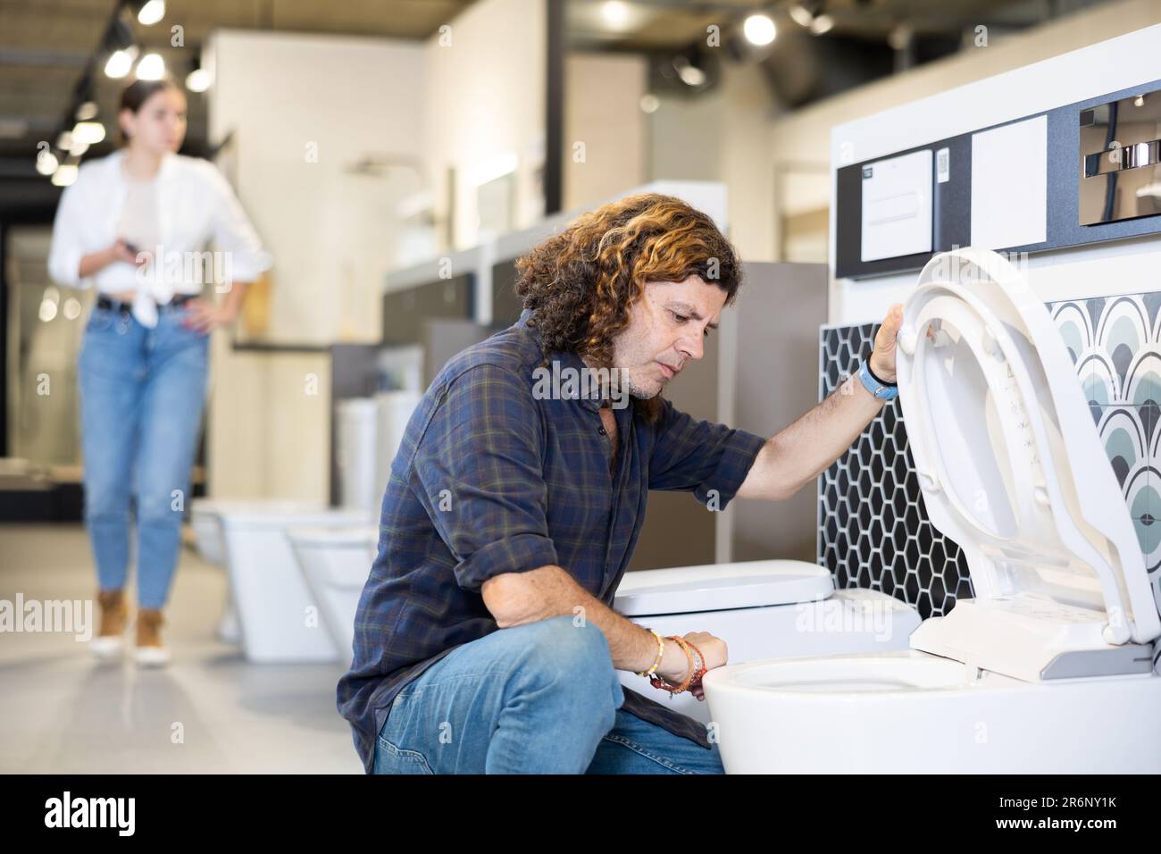 in plumbing department, male buyer checks for defects of toilet before ...