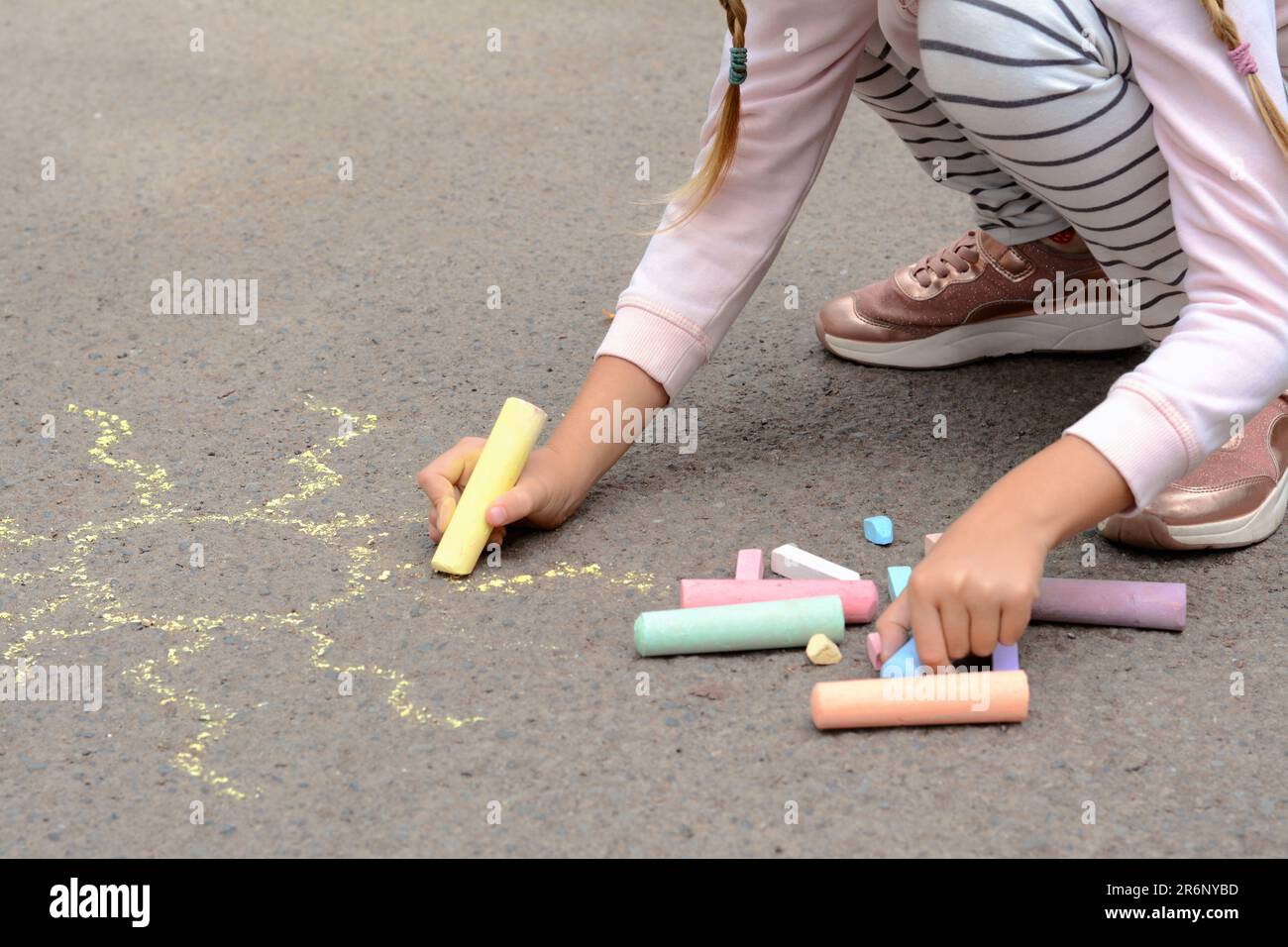 Little child drawing sun with chalk on asphalt, closeup Stock Photo - Alamy