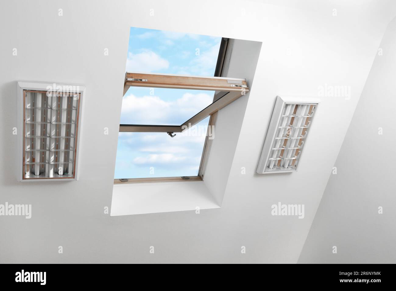 Open skylight roof window on slanted ceiling in attic room, bottom view ...