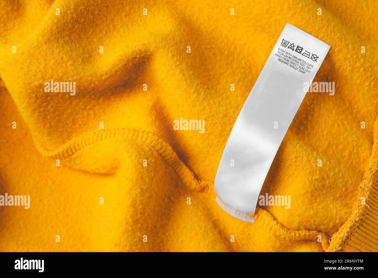 Clothing label with care recommendations on orange garment, top view ...