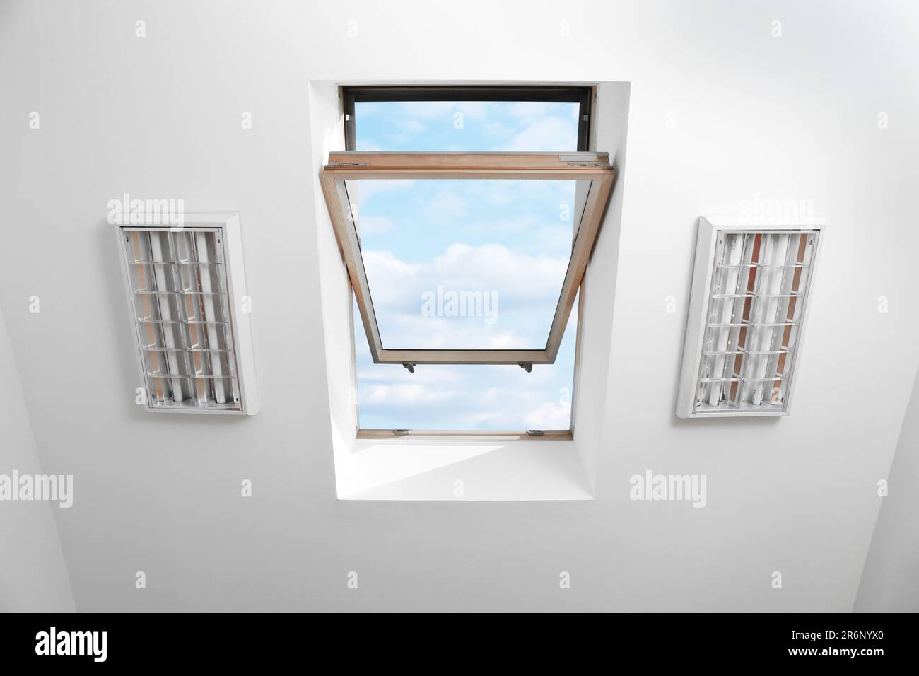 Open skylight roof window on slanted ceiling in attic room, bottom view ...