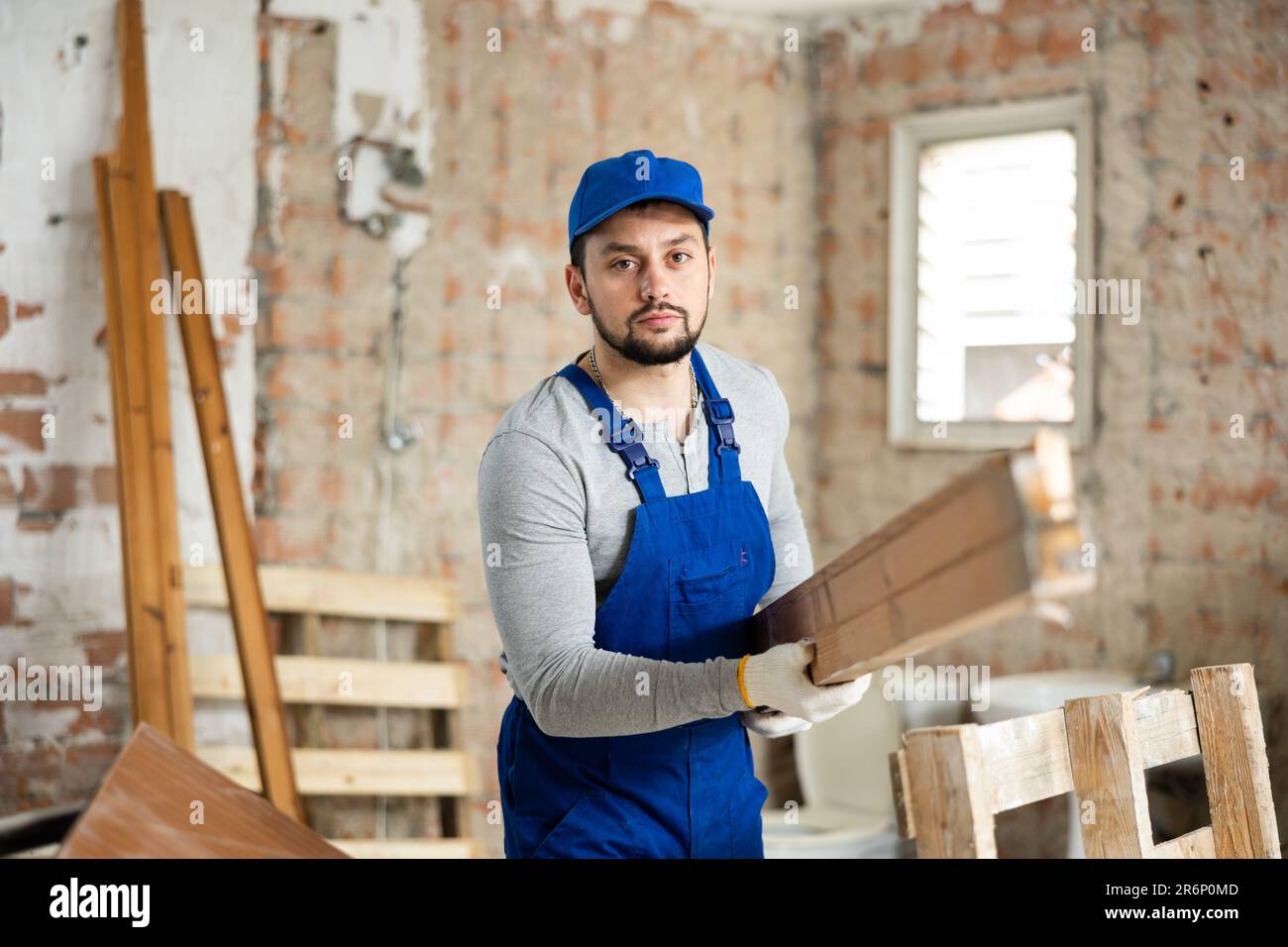 Man carrying wooden materials at construction site Stock Photo - Alamy