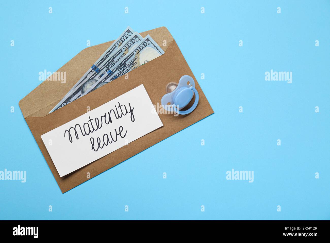 Maternity leave concept. Envelope with dollar banknotes, pacifier and ...