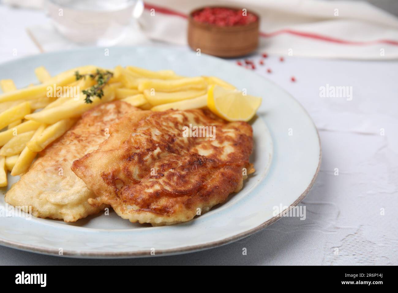 Tasty soda water battered fish, potato chips and lemon slice served on ...