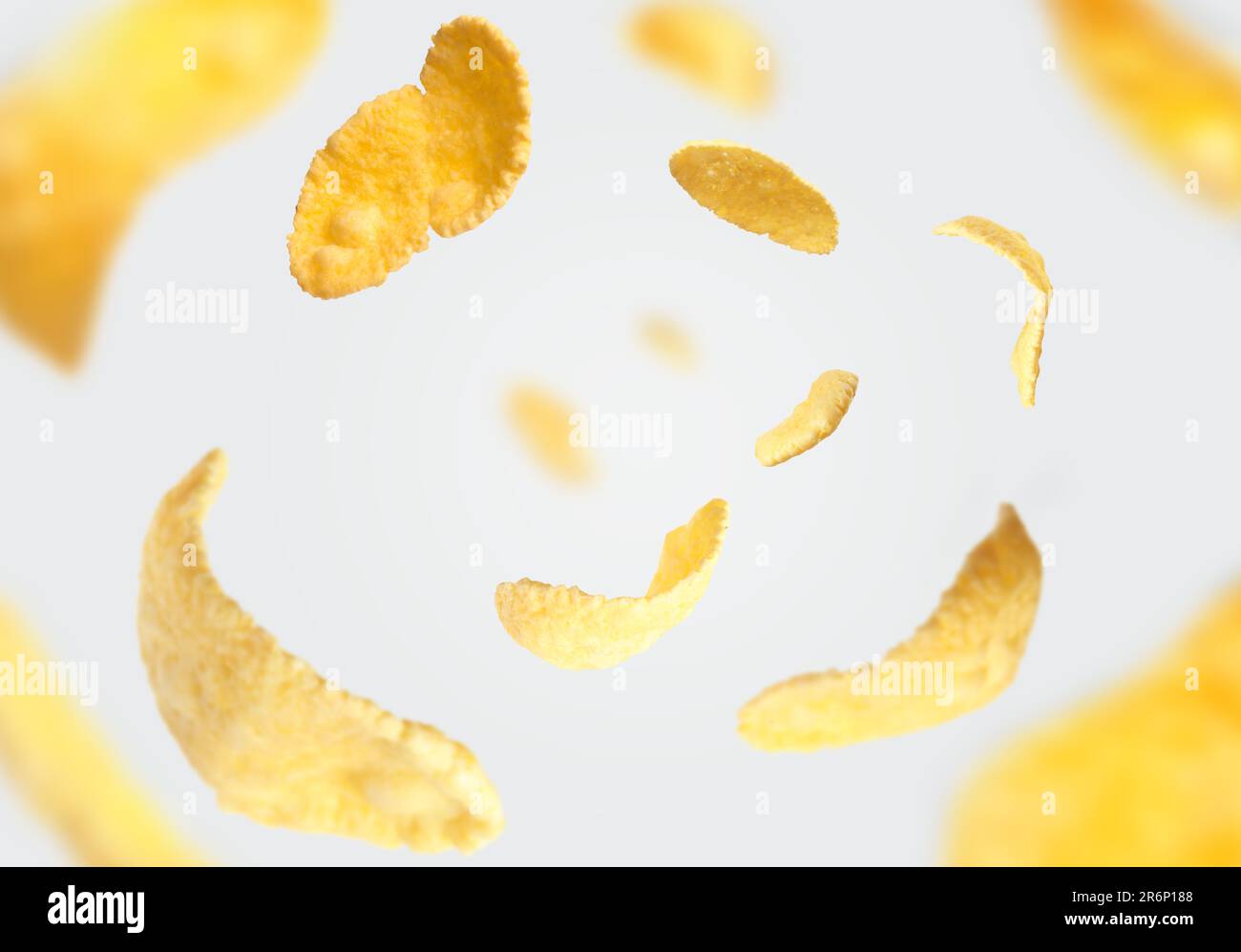 Many tasty corn flakes falling on white background Stock Photo - Alamy