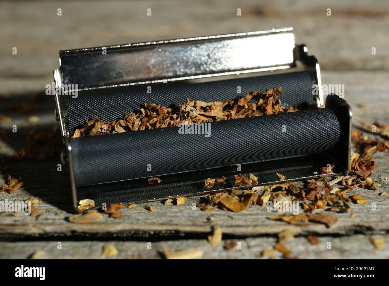 Roller with tobacco on old wooden table, closeup. Making hand rolled ...
