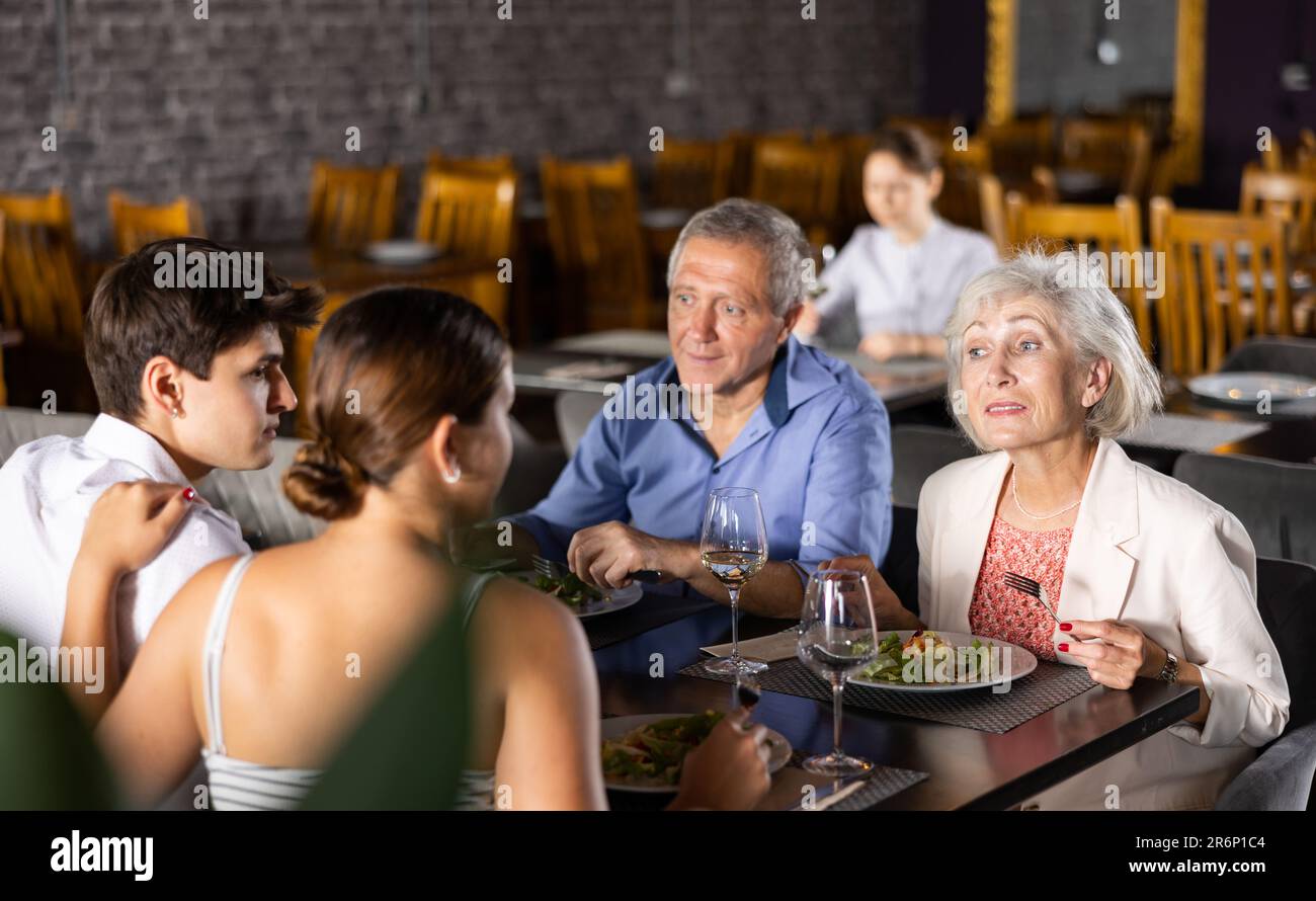 Elderly couple and young couple having dinner in restaurant Stock Photo ...