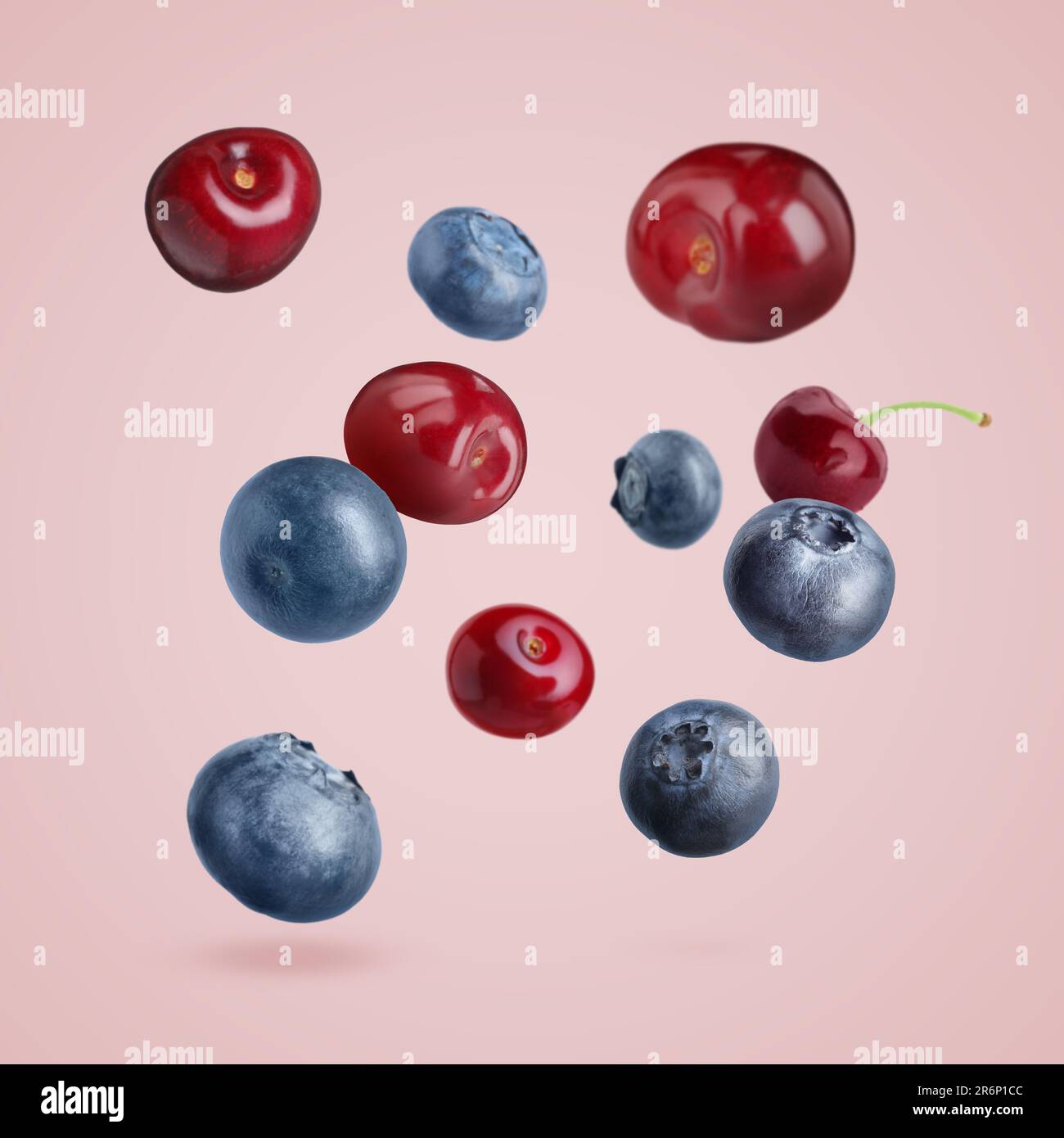 Blueberries and cherries falling on pale pink background Stock Photo ...
