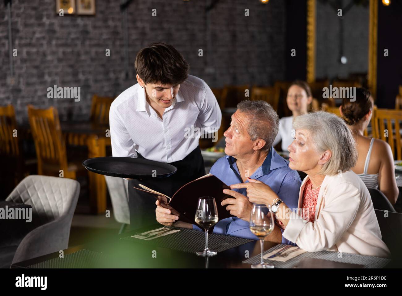Young male waiter takes order from elderly couple in restaurant Stock ...