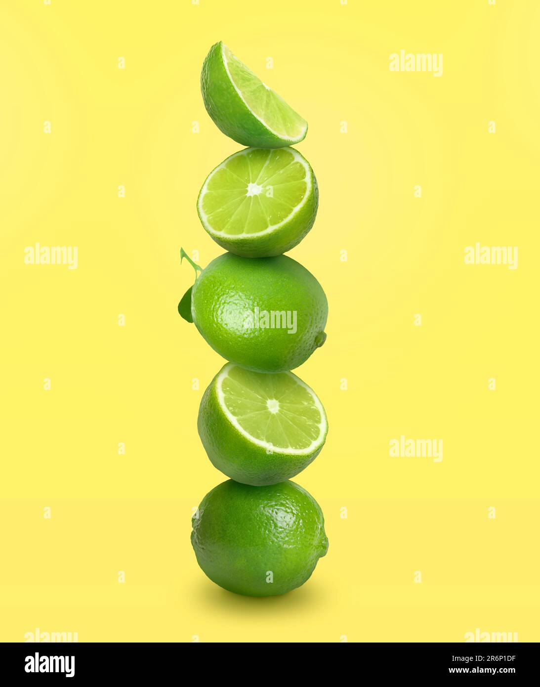 Stacked whole and cut limes on yellow background Stock Photo - Alamy