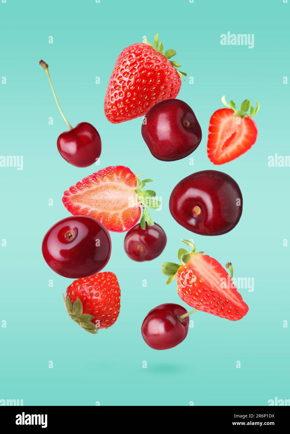 Strawberries and cherries falling on turquoise background Stock Photo ...