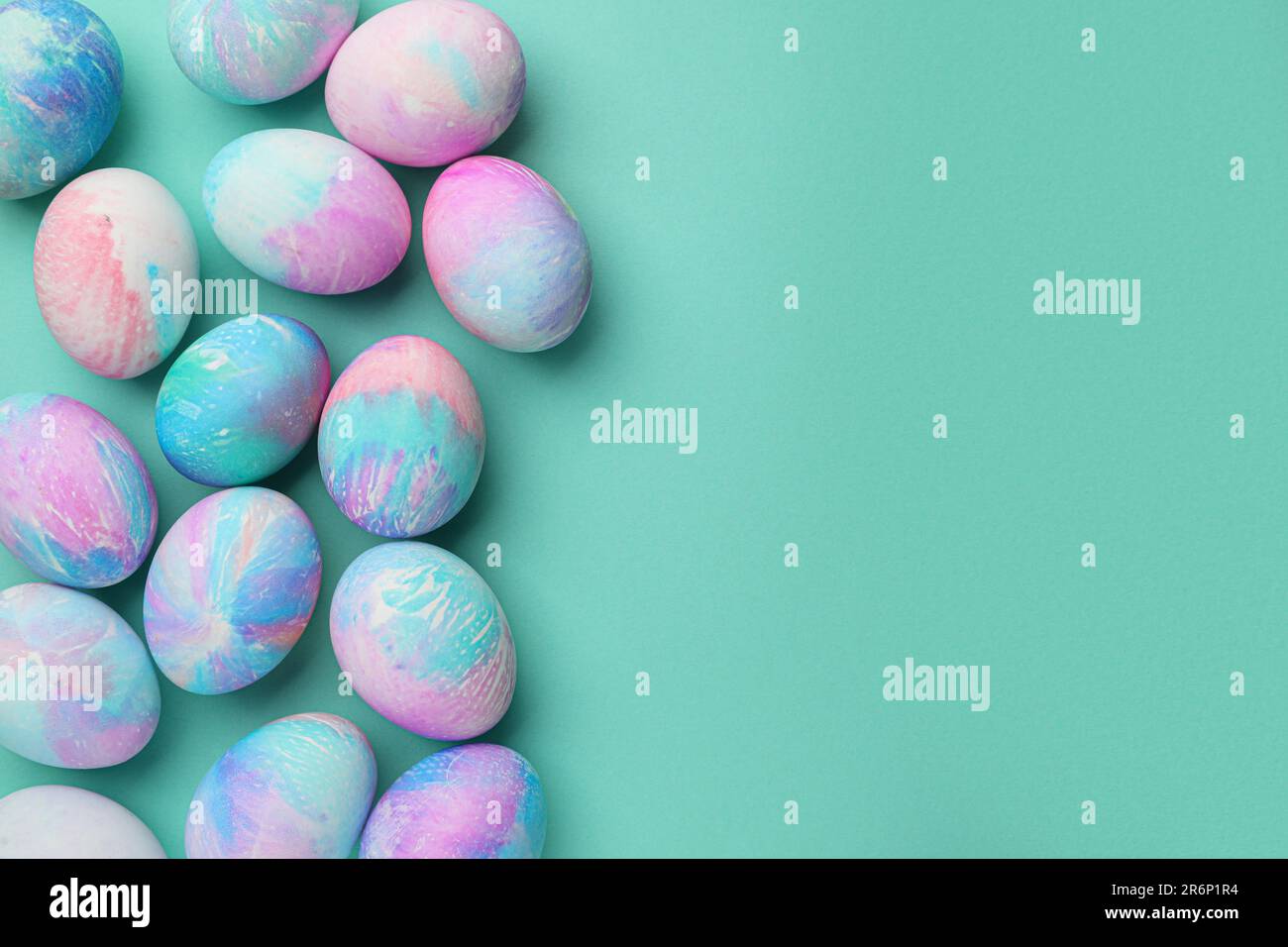 Many decorated Easter eggs on turquoise background, flat lay. Space for ...