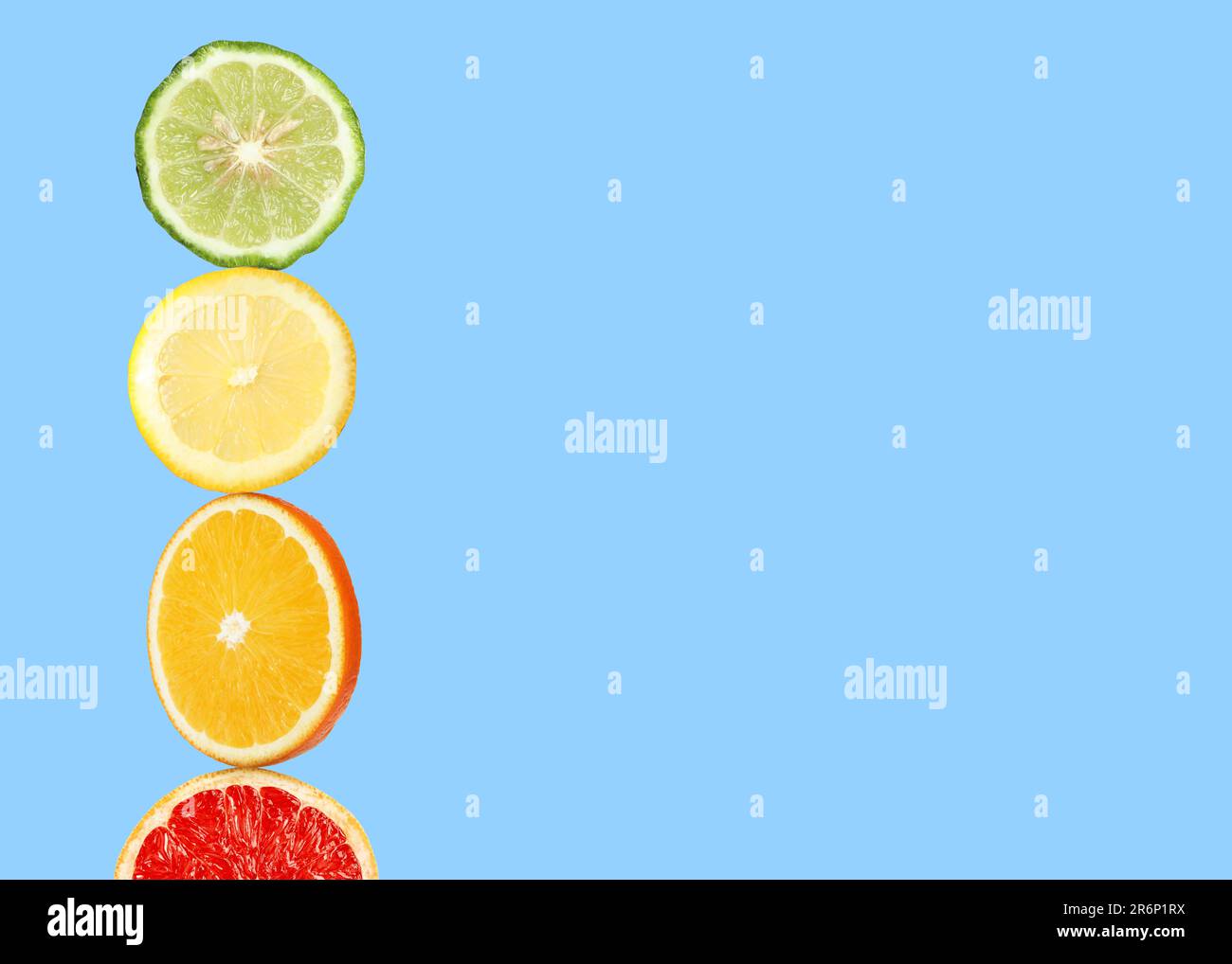 Stack of different fresh citrus fruits on light blue background, space ...