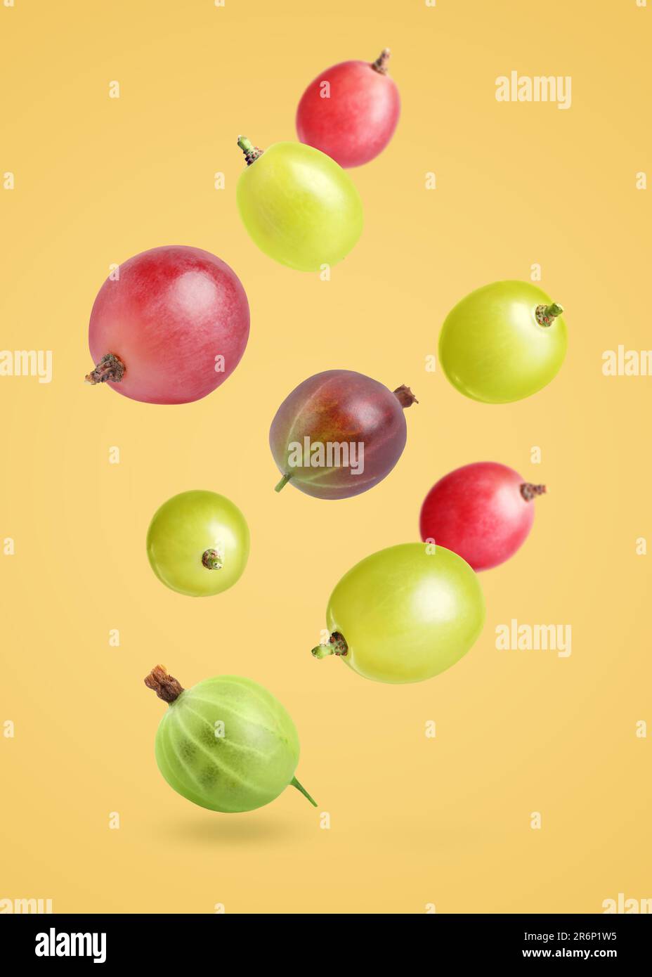 Fresh grapes and gooseberries falling on dusty yellow background Stock ...