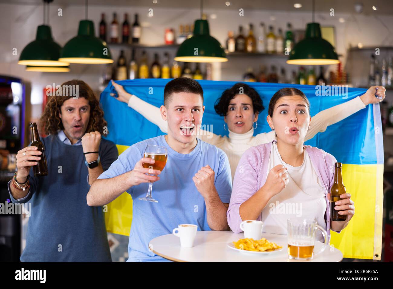 Emotional young adult sports fans waving Ukrainian flag while watching ...