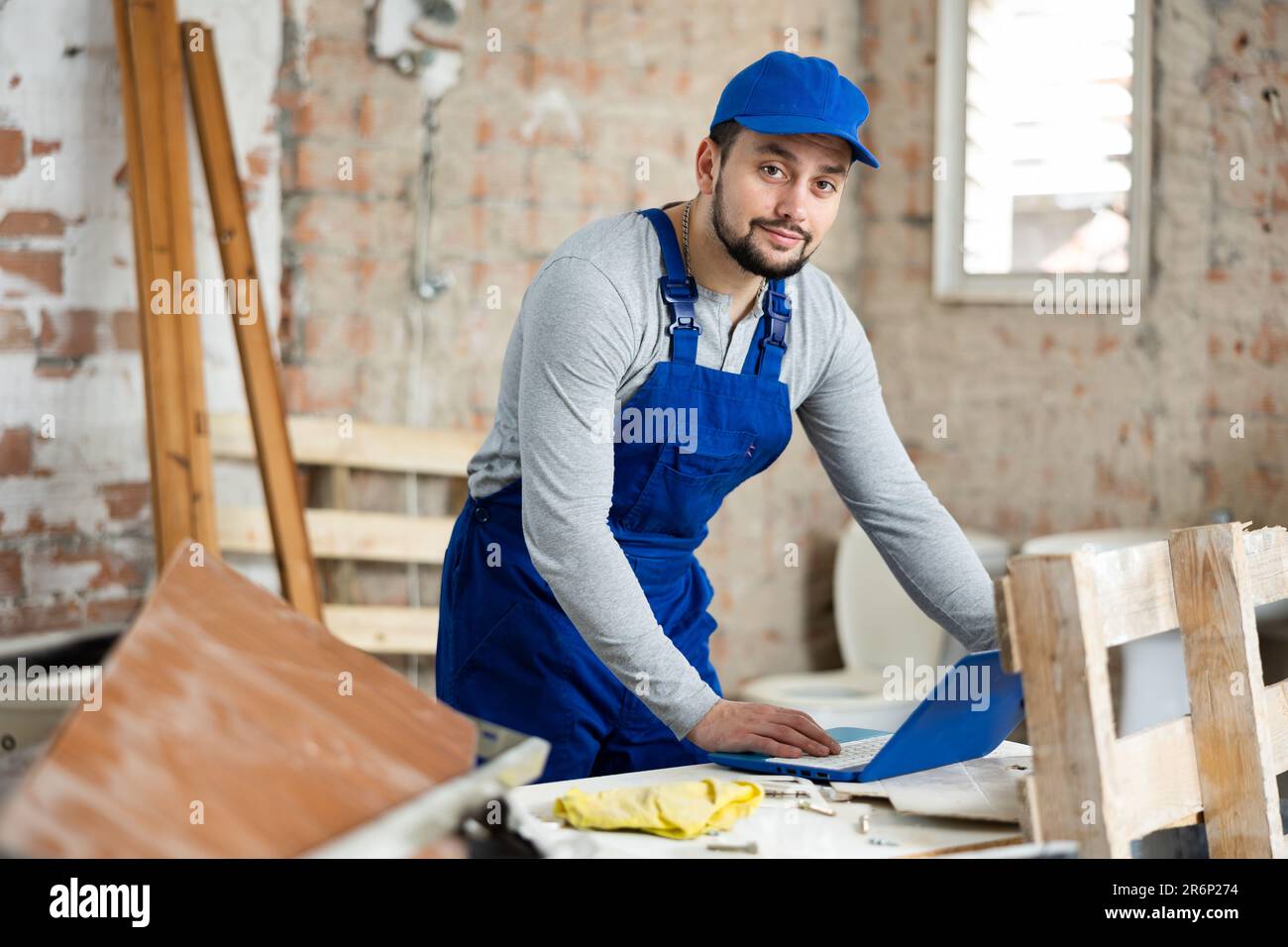 Builder checks the house repair plan on a laptop Stock Photo - Alamy