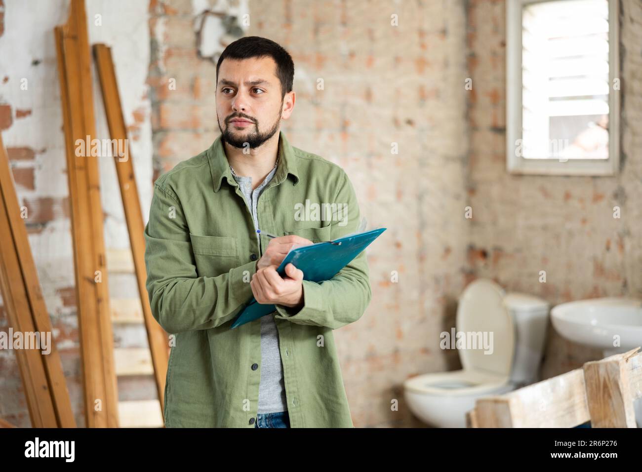 Engineer planning renovation works at building site, looking at papers ...
