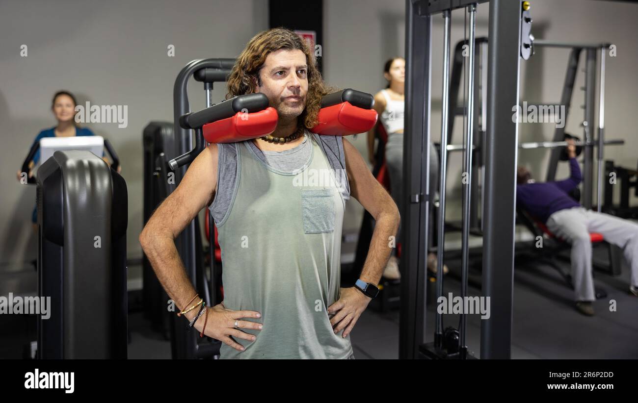 Muscular man is engaged on simulator to strengthen muscles of legs in ...