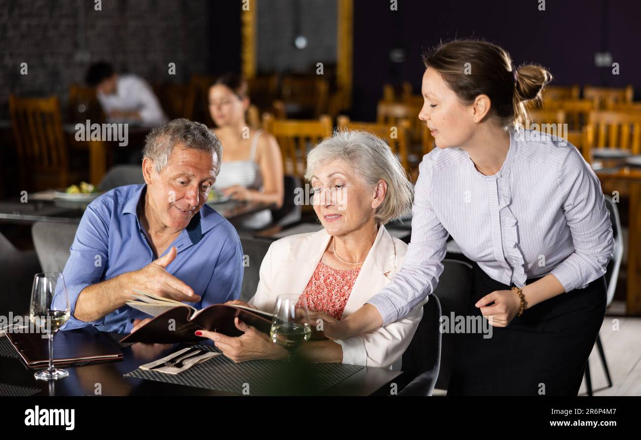 Woman waiter taking order from elderly couple in restaurant Stock Photo ...