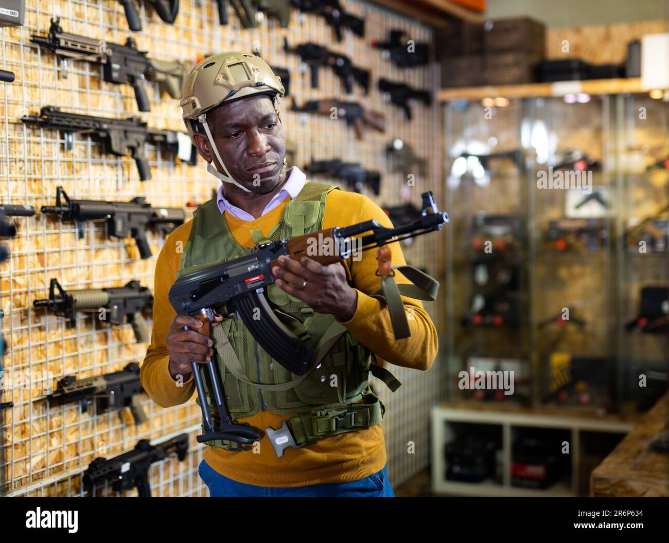 Man in armor vest selecting machine gun in weapon shop Stock Photo - Alamy