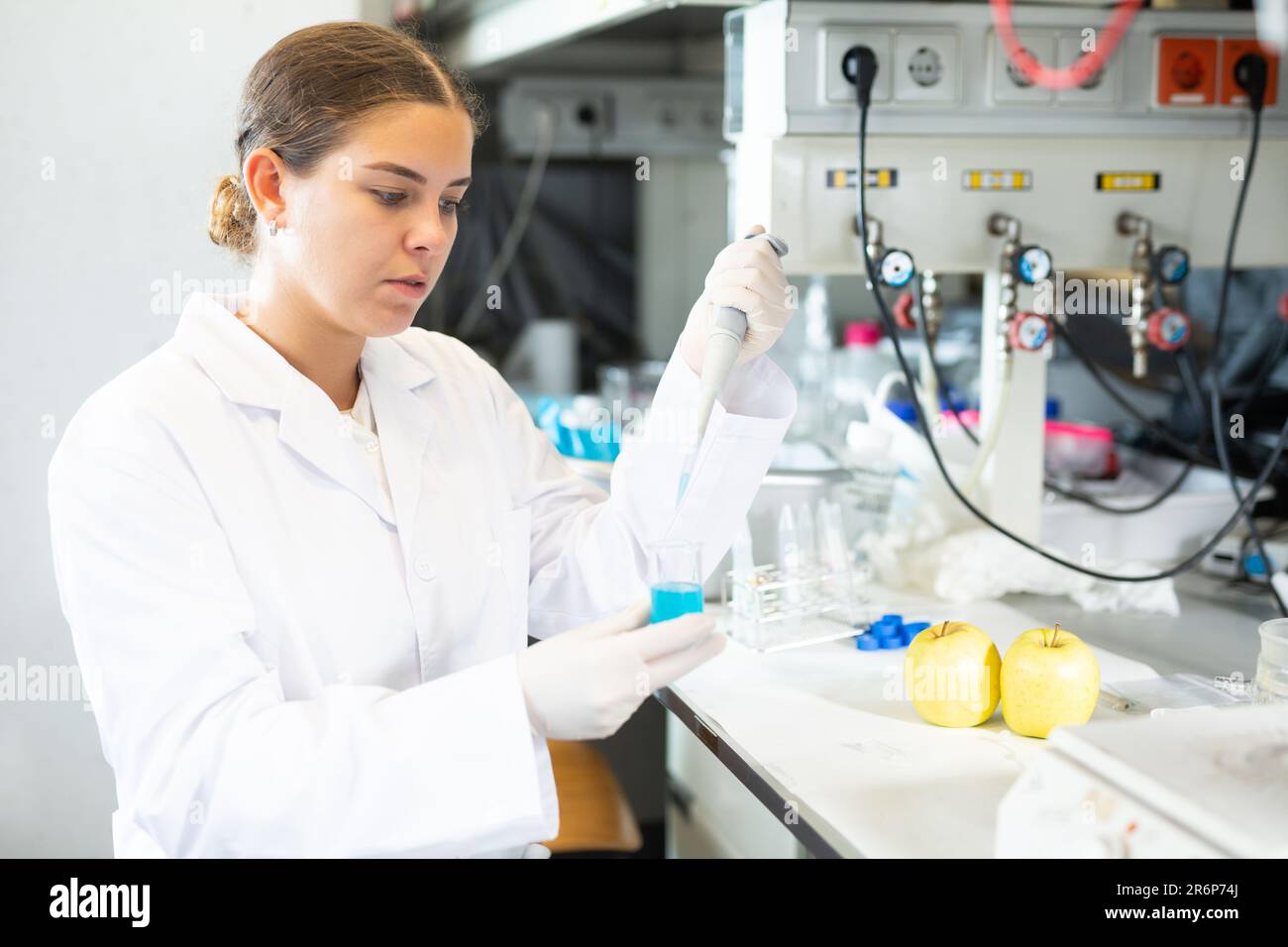 Clever female researcher in white coat mixing reagents in test tube ...