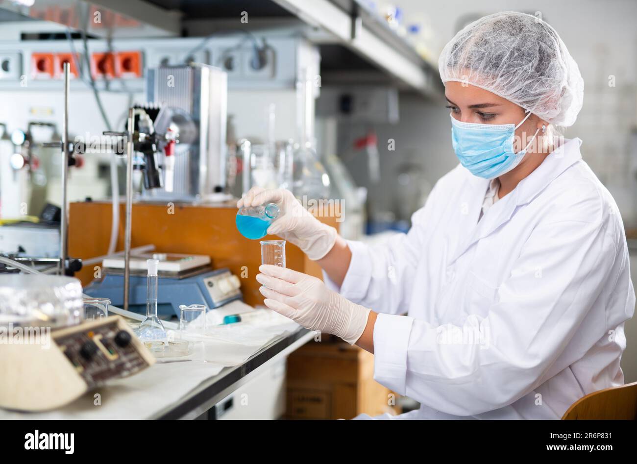 Female scientist making research pouring blue reagent into test tubes ...
