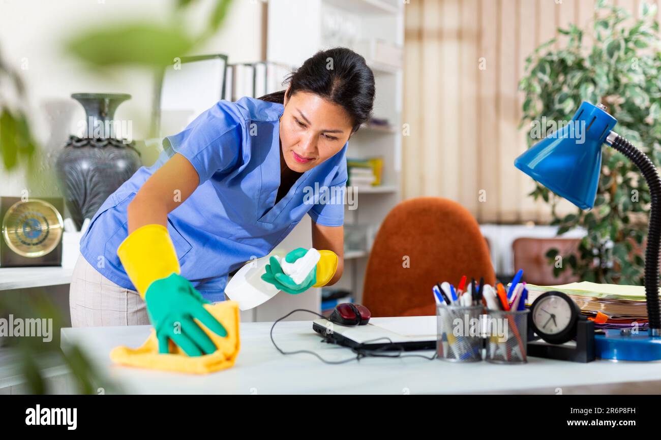 Asian female cleaning desk in office Stock Photo - Alamy