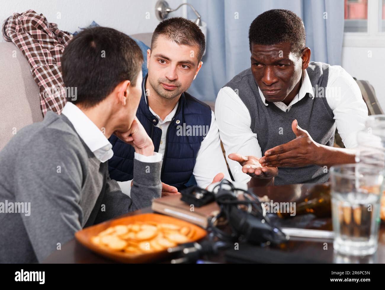 Friends calming distressed guy Stock Photo - Alamy