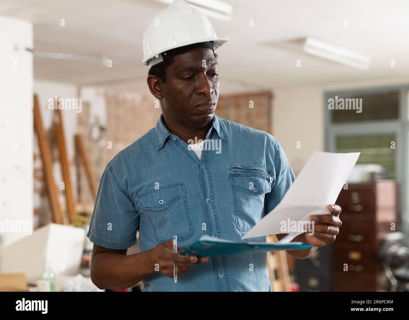 Strict building inspector standing with papers at construction site ...