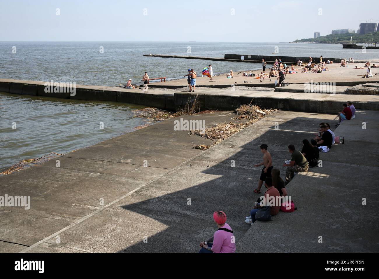 People rest on the coast of Lanzheron beach near rubbish and reeds ...