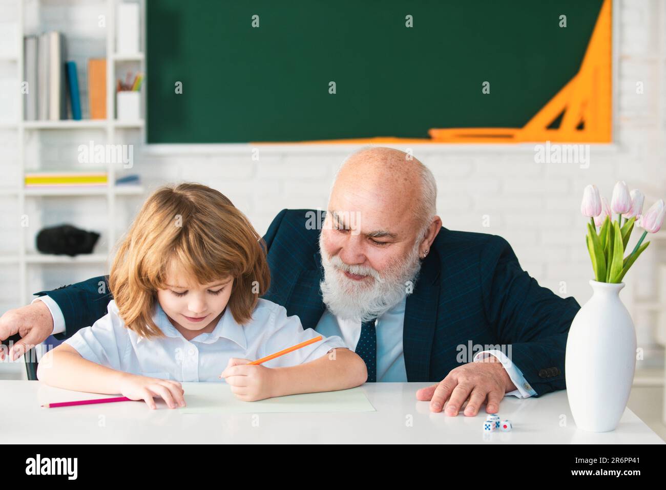 Senior teacher or grandfather and school boy pupil in classroom at ...