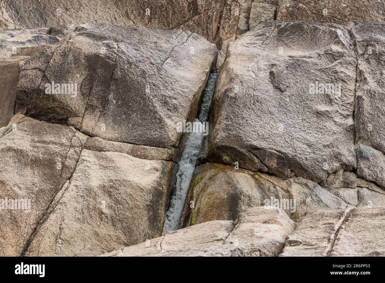 Water flowing down a small waterfall in a cliff face in outback QLD ...