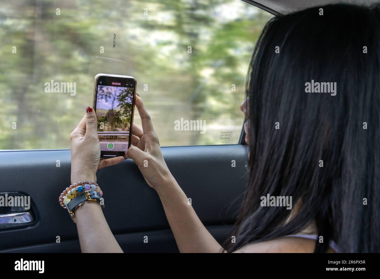 A girl takes a video of a mountain landscape through the window of a ...