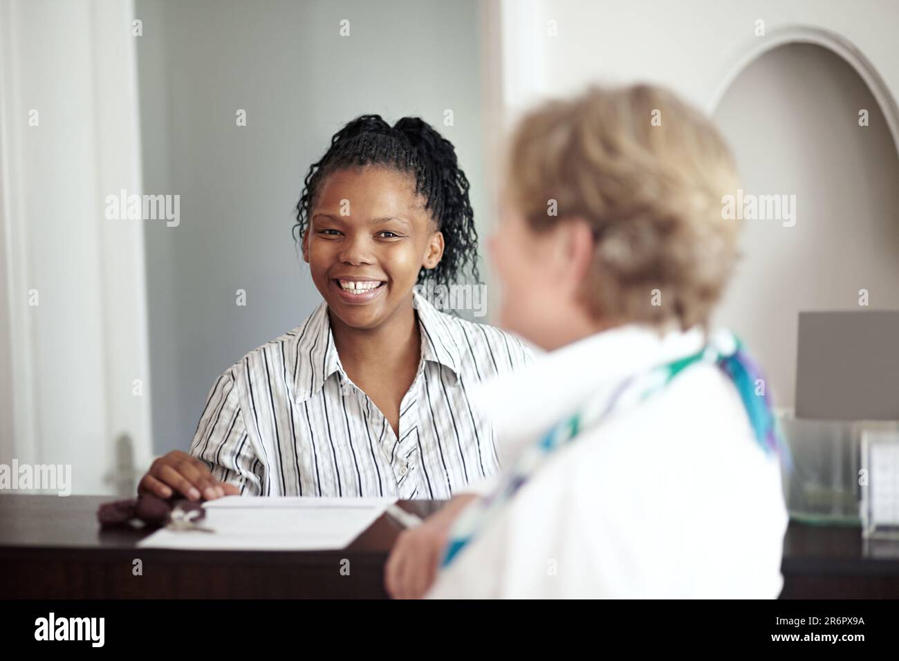 Hotel receptionist, concierge and a black woman helping a senior ...
