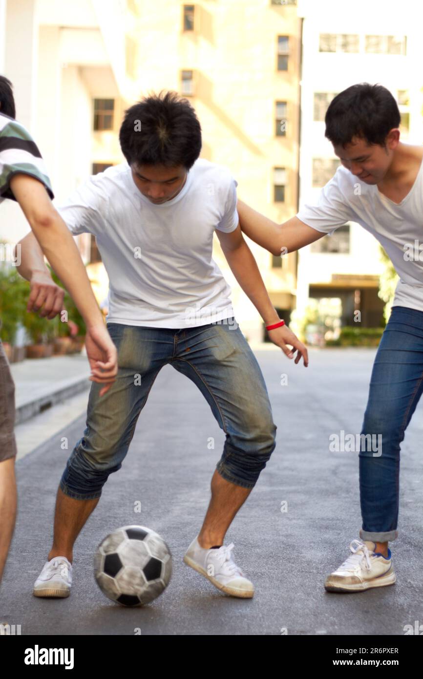 Friends in road playing with soccer ball together for sports, fun and ...