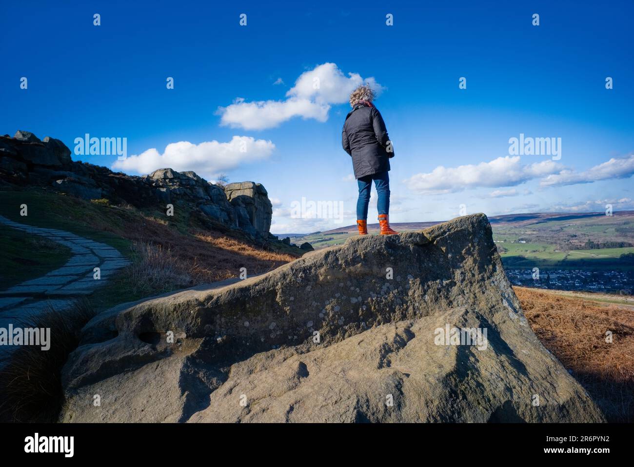 Woman standing at Cow and Calf Rocks high above Yorkshire town Ilkley ...