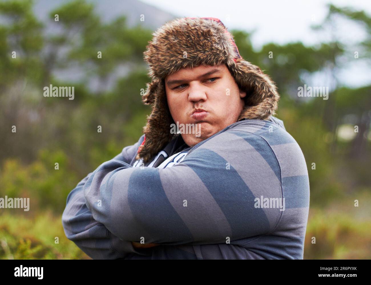 Angry, frustrated and young overweight man in nature during winter ...