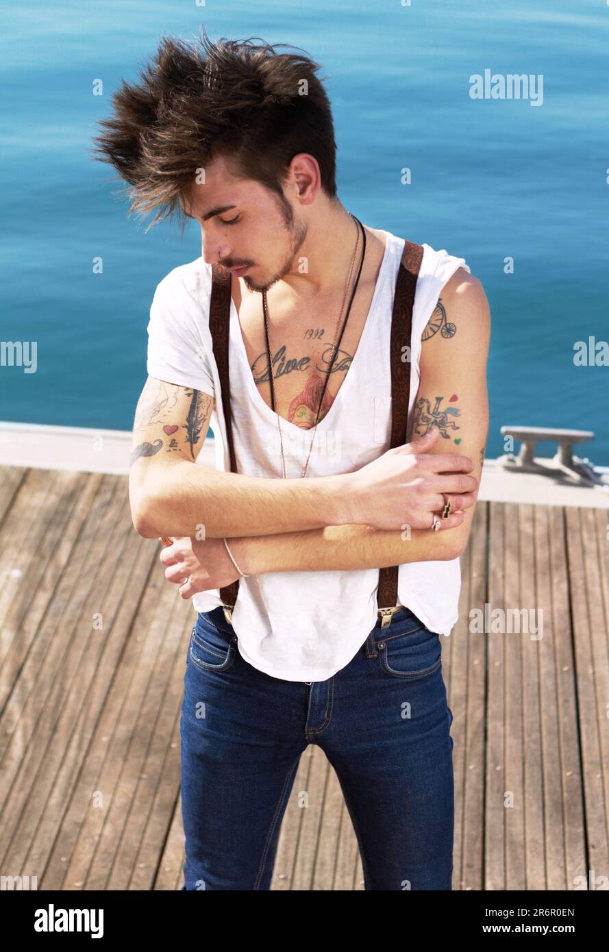 Punk dress code, man with tattoos and on pier outdoors at the beach ...